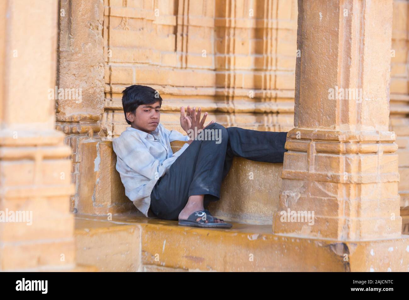Jaisalmer, India - March 10 2017: A sad boy is sitting on a stone bench ...
