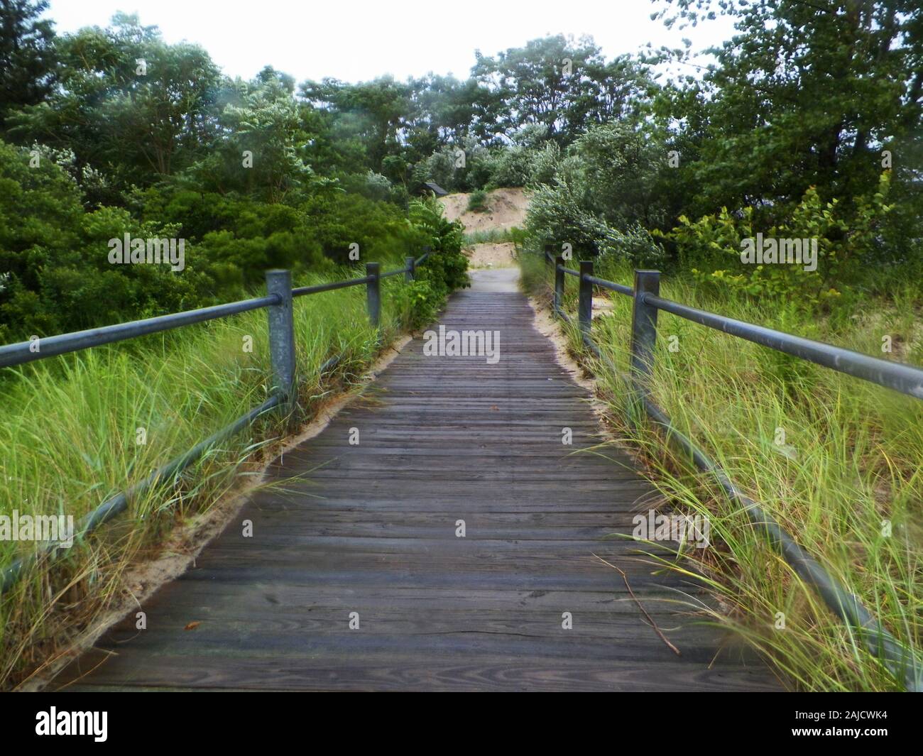 Boardwalk pathway flanked by metal fences leads to beach Stock Photo ...