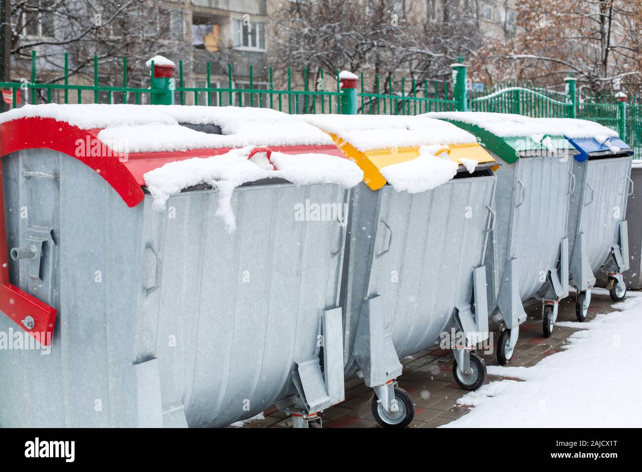 Trash bins for sorting garbage are standing on the street covered with ...