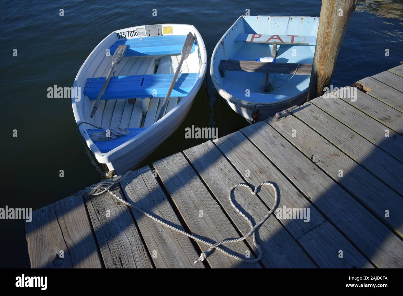 Two dinghies or row boats tied up to a dockwith a rope made out of a ...