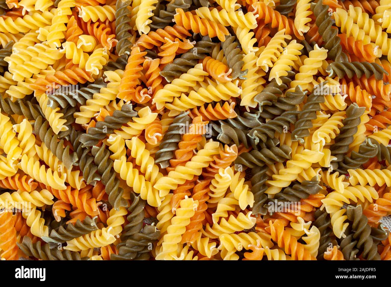 Colourful background of raw tricolore fusilli Italian pasta Stock Photo ...