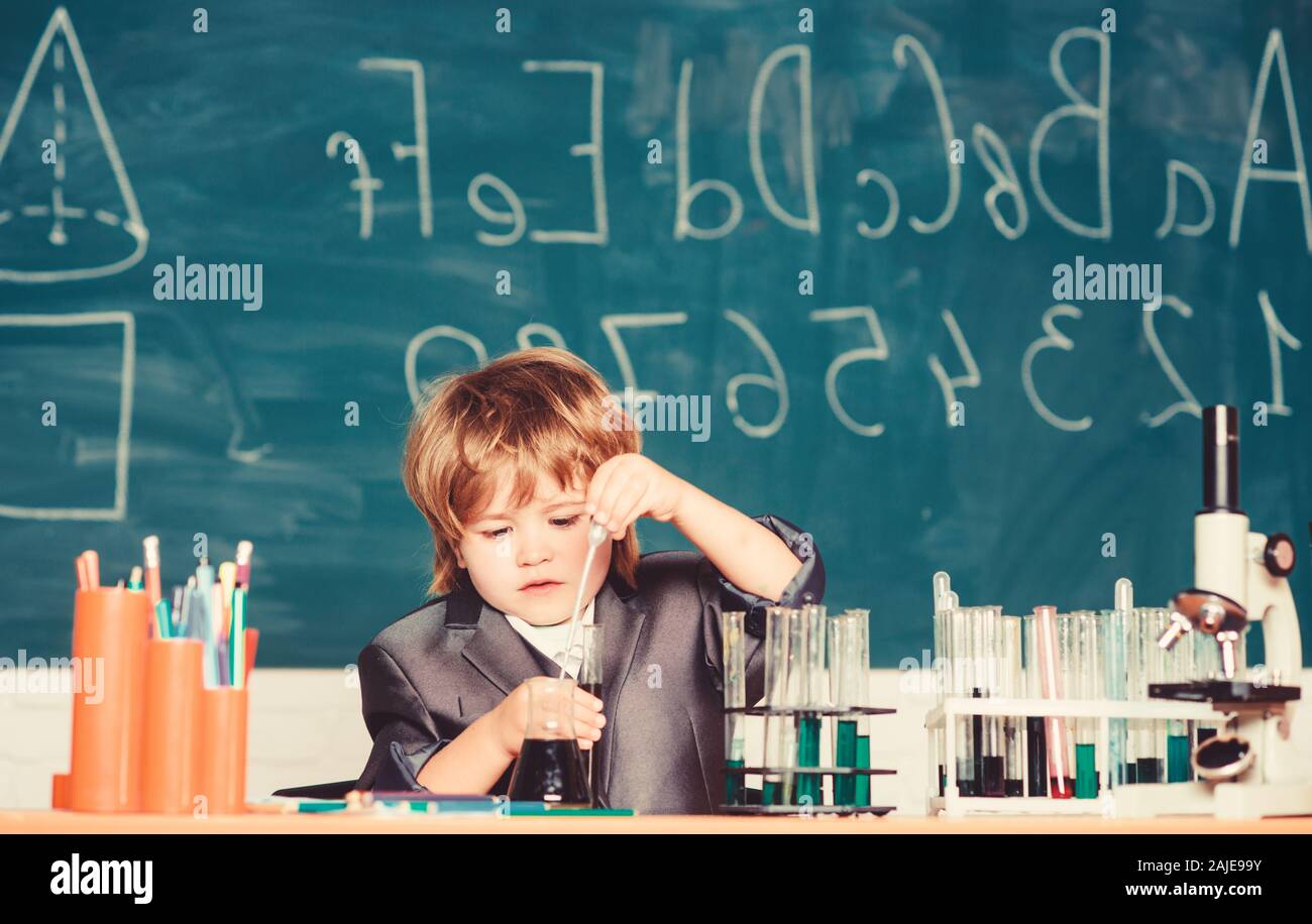 Happy childhood. Boy near microscope and test tubes school classroom ...