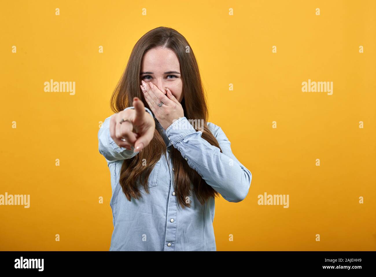 Attractive caucasian woman covered nose with hand, pointing finger at ...