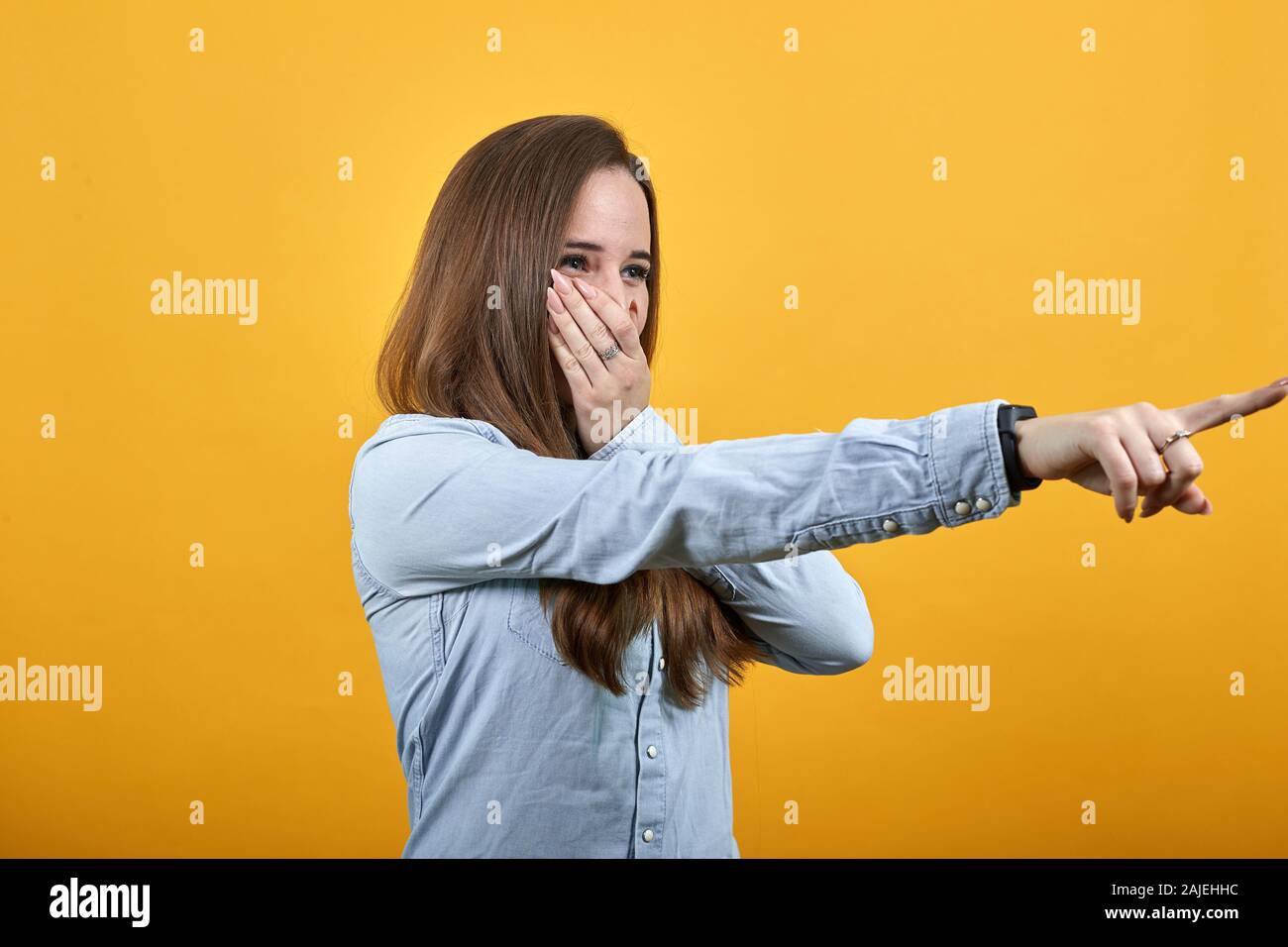 Shocked attractive woman covered mouth with hand, pointing finger into ...