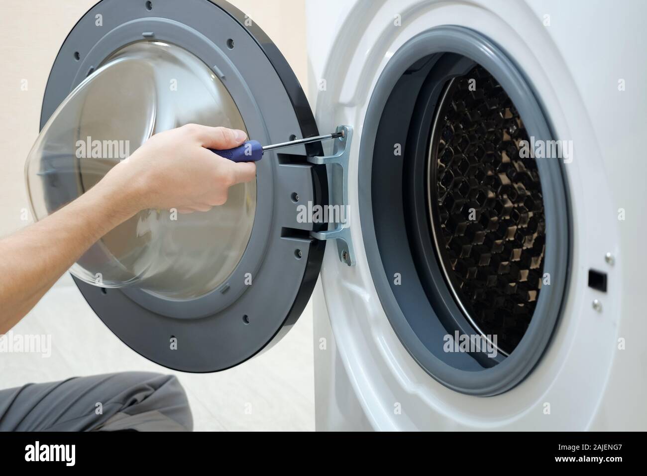 professional repairman twisting screw on broken washing machine door ...