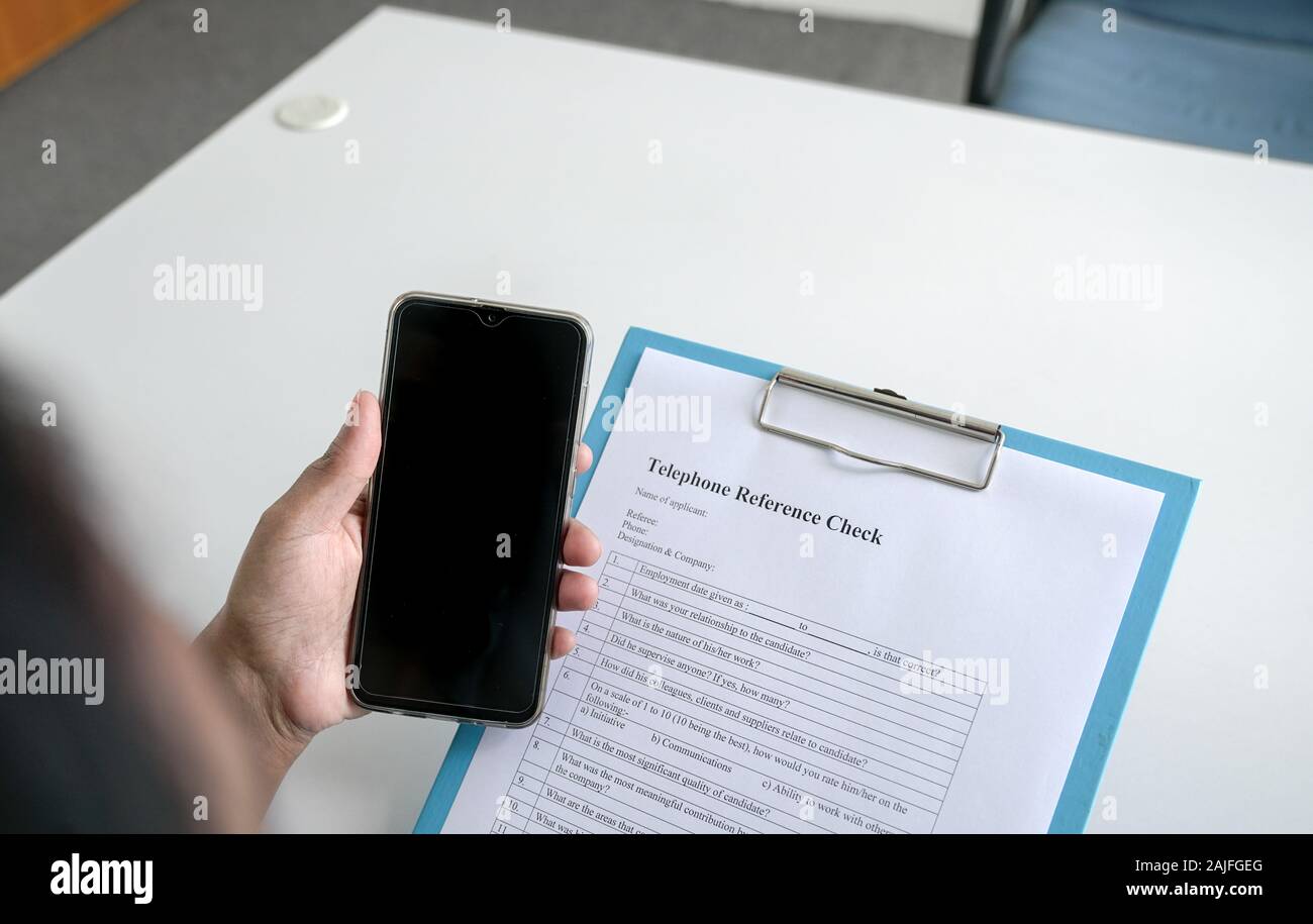 Making a call to conduct a telephone reference check on a potential ...
