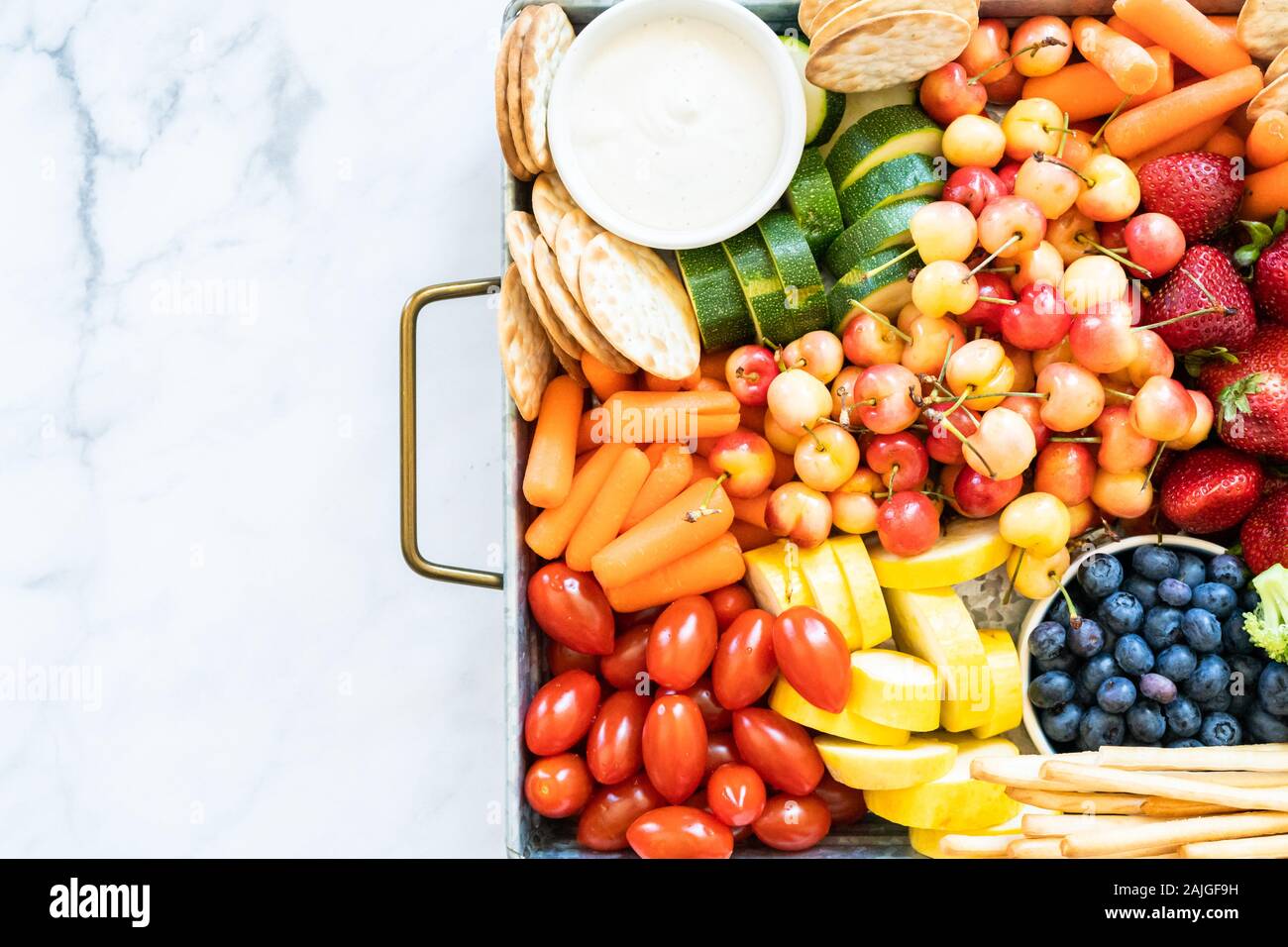 Snack board with fresh fruit, vegetables, crackers, and dips Stock ...