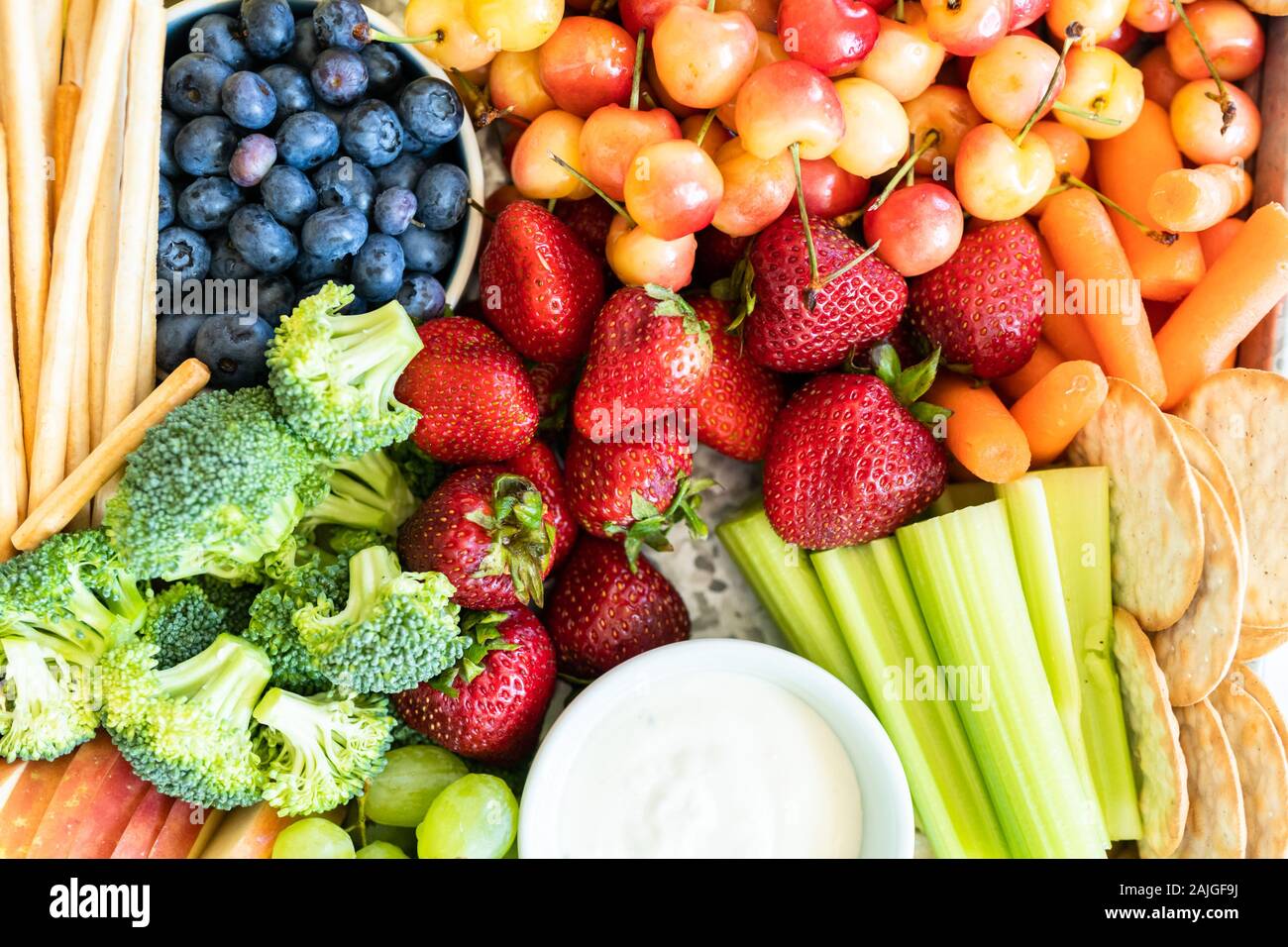 Snack board with fresh fruit, vegetables, crackers, and dips Stock ...