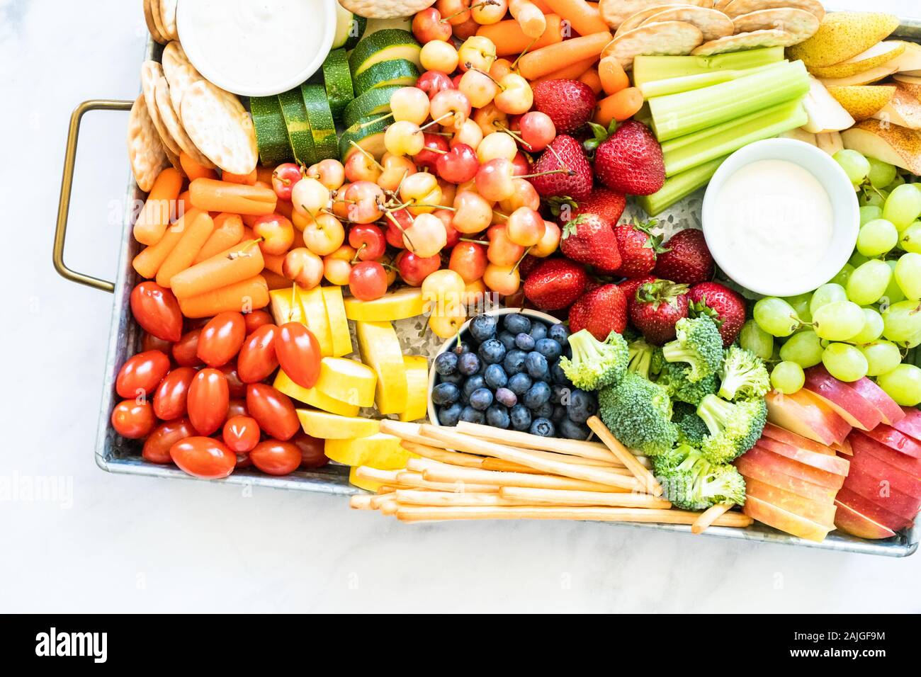Snack board with fresh fruit, vegetables, crackers, and dips Stock ...