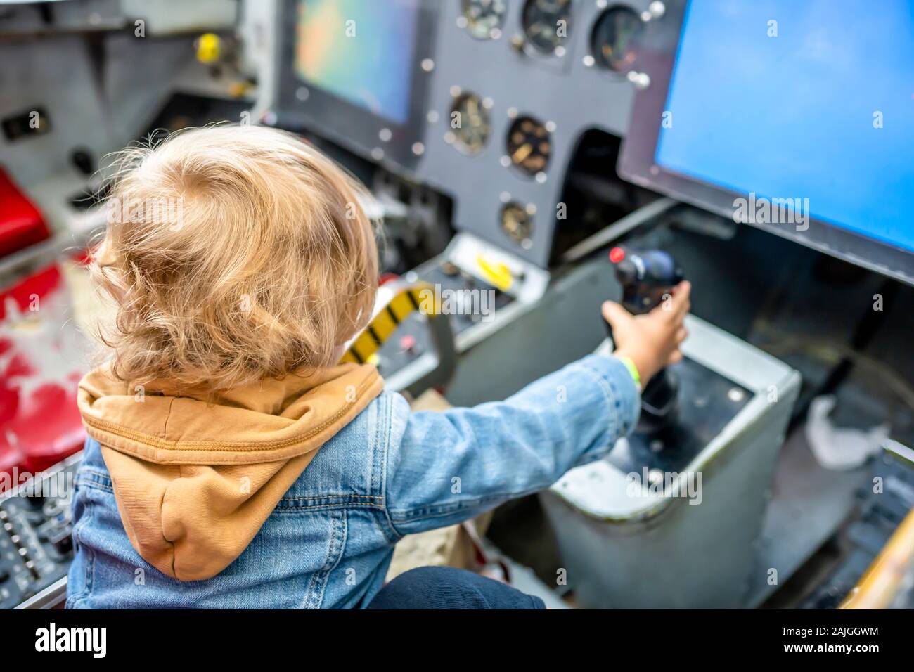 A child with curly blond hair is fascinated by the space flight control ...