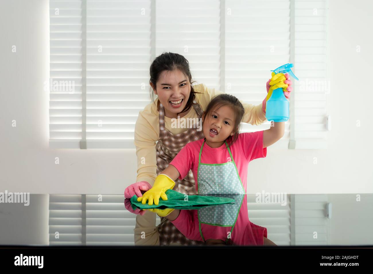 Asian Cheerful mother and daughter cleaning table surface with rag and ...