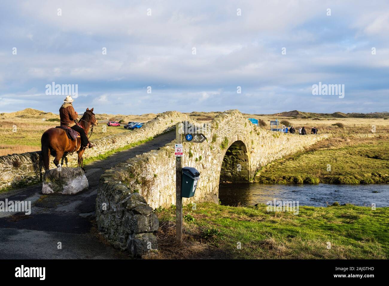 Man on horseback riding a brown horse over the old bridge (Hen Bont ...