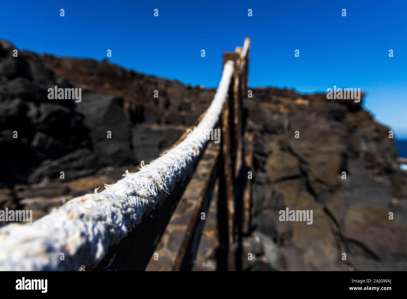 Weathered rope handrail on steps over volcanic rock at Playa de Sibora ...