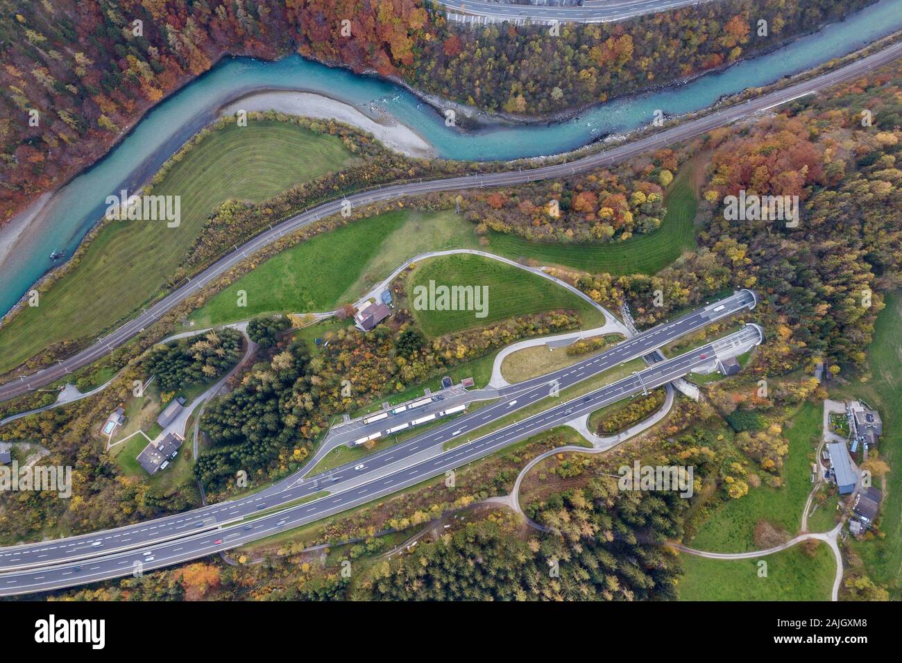 Top dawn aerial view of freeway speed road going out from undeground tunnel between yellow ...