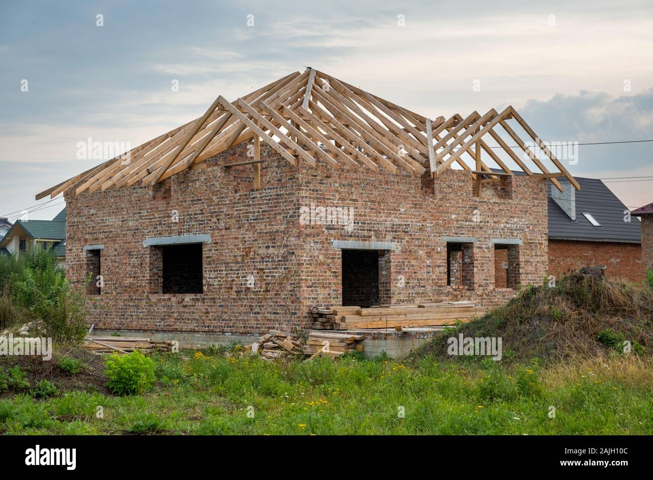 Building site with unfinished brick house with wooden roofing frame for ...