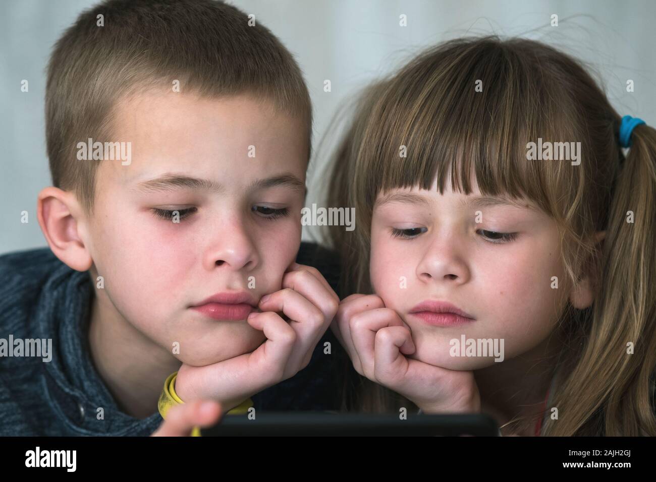 Two children brother and sister watching video on smartphone screen ...