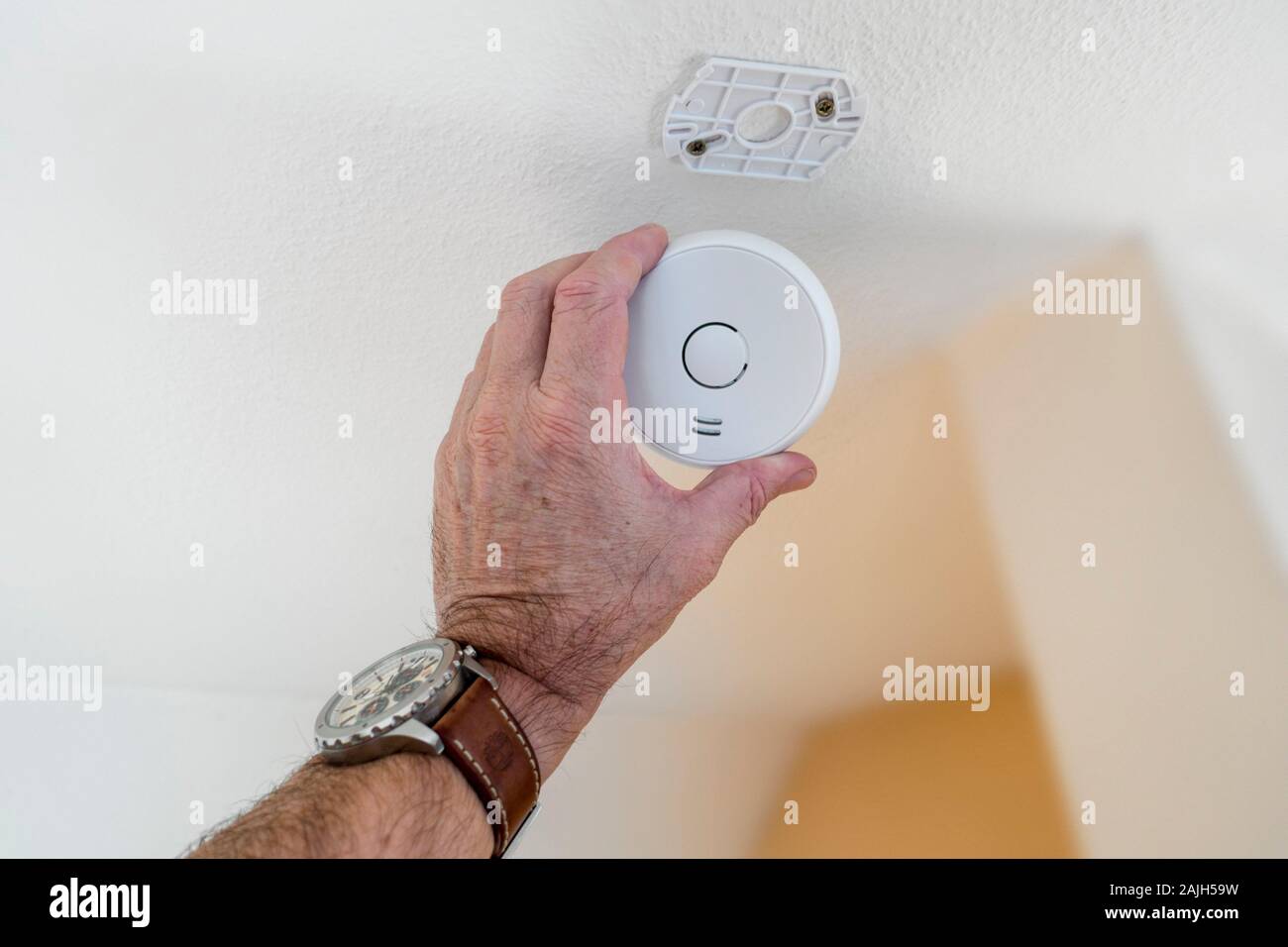 Man fitting domestic smoke alarm / battery powered smoke detector on ...