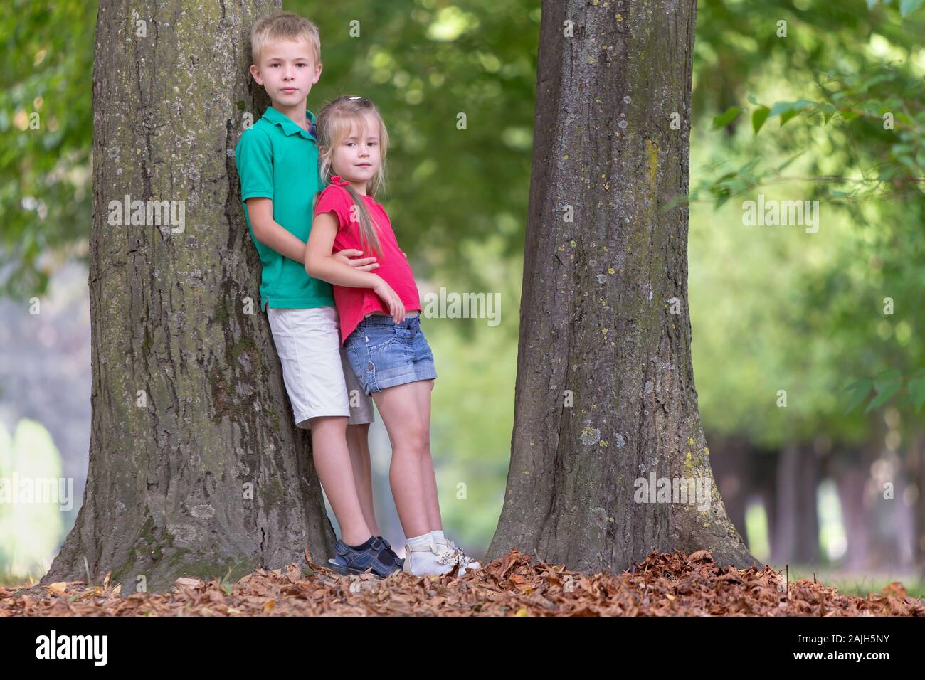 Portrait of two pretty cute children boy and girl standing near big ...