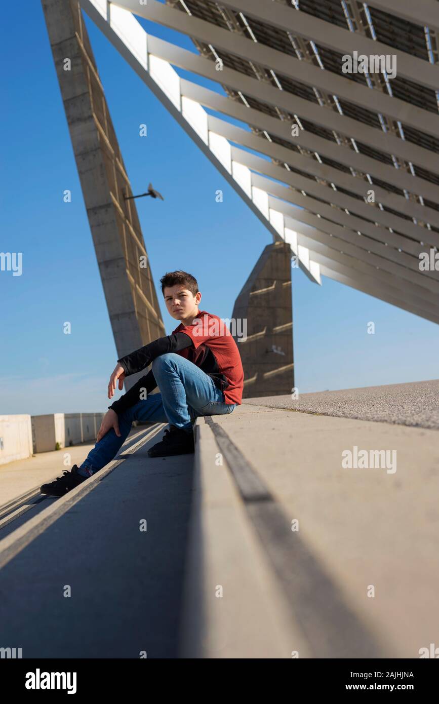 Young teen sitting on stairs outdoors, looking camera in sunny day ...