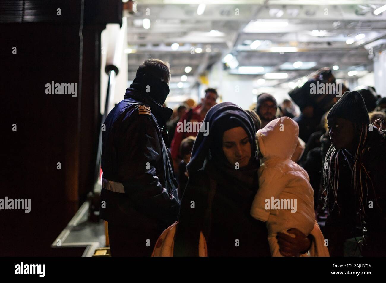 A refugee carrying her kid disembarks from a Nisos Chios ship at the ...