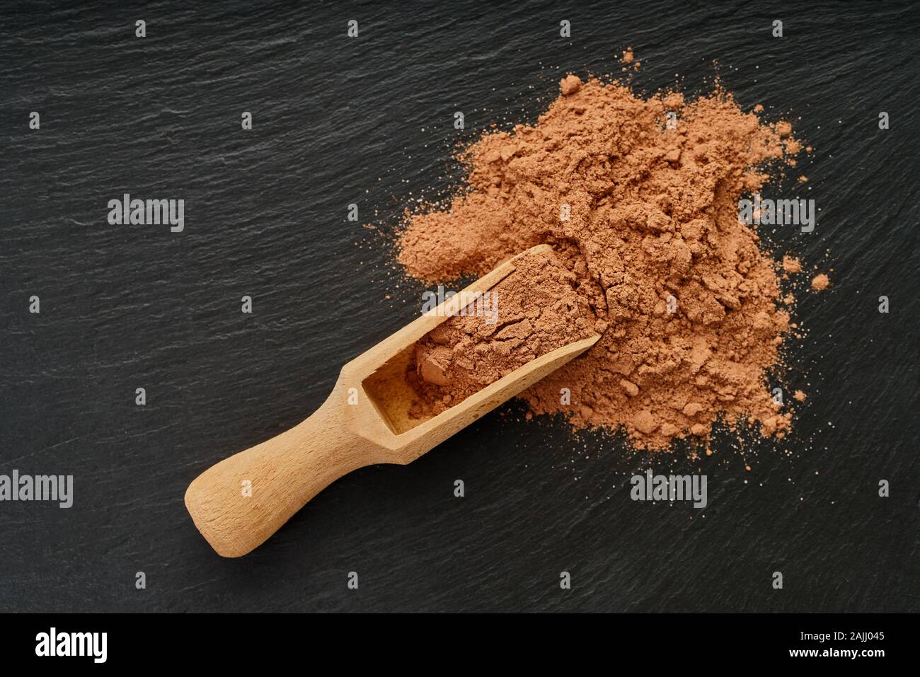 cocoa powder in a wooden scoop on black background Stock Photo - Alamy