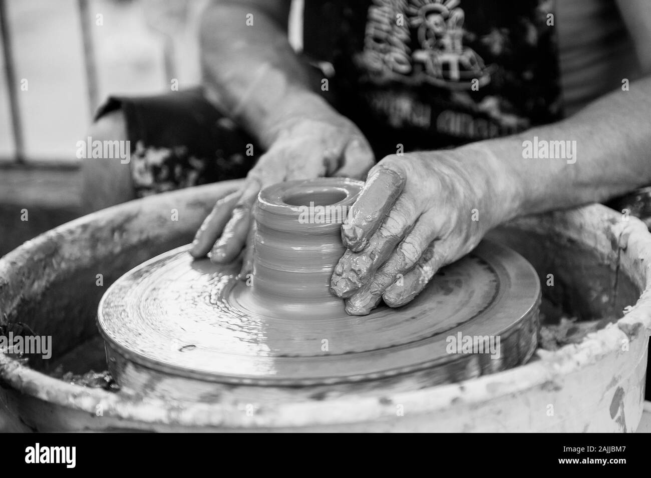 The potter makes pottery dishes on potter's wheel. The sculptor in ...