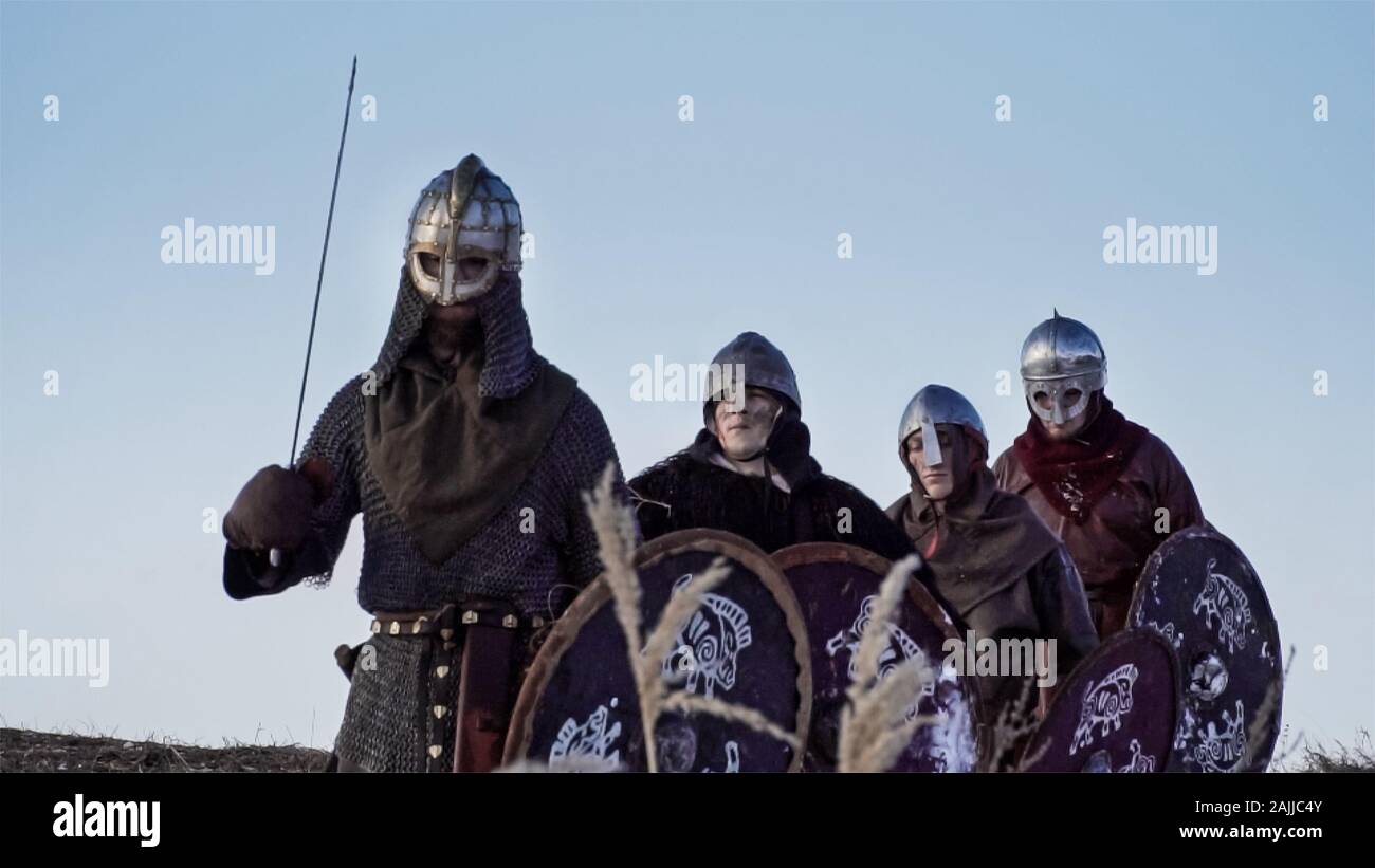 Back view of a group of medieval vikings with arms and shields going on ...