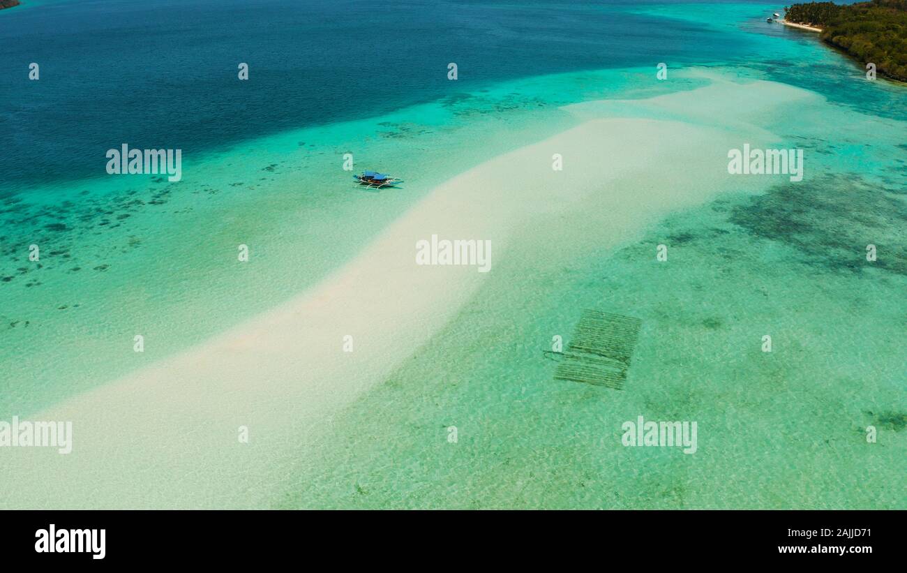 Island with a sandy beach and azure water surrounded by a coral reef ...