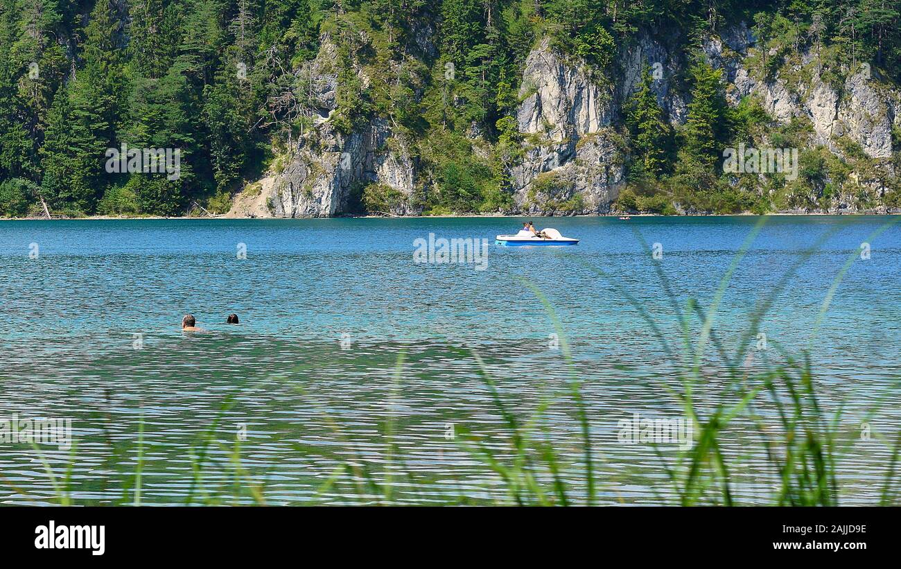 People swimming and boating on the Alpsee in the town of Hohenschwangau ...
