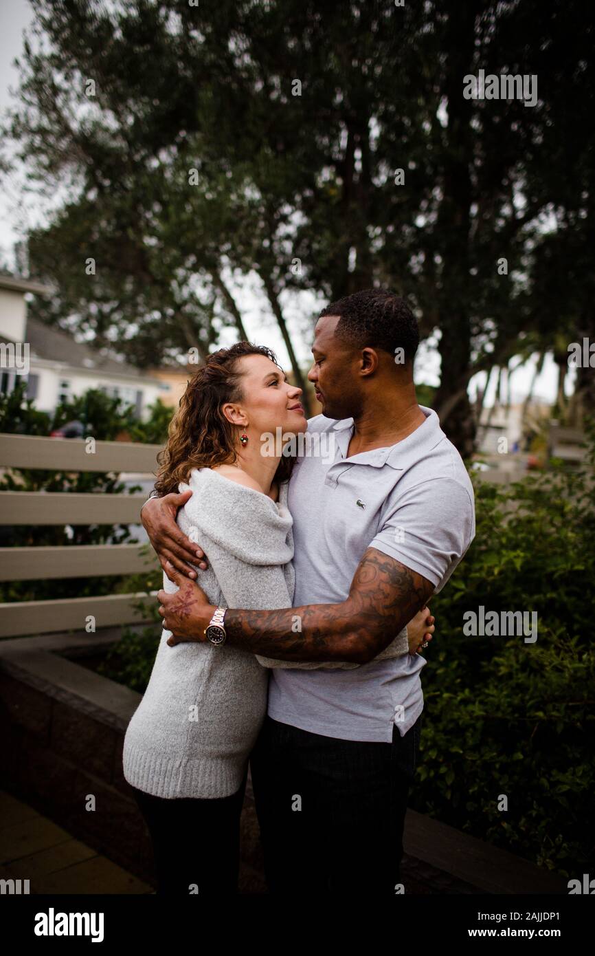 Biracial Couple Embracing & Looking at one Another Stock Photo - Alamy