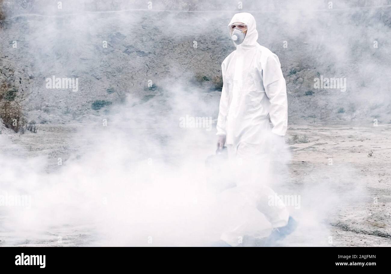 Lab technician in a mask and chemical protective suit, walks on dry ...