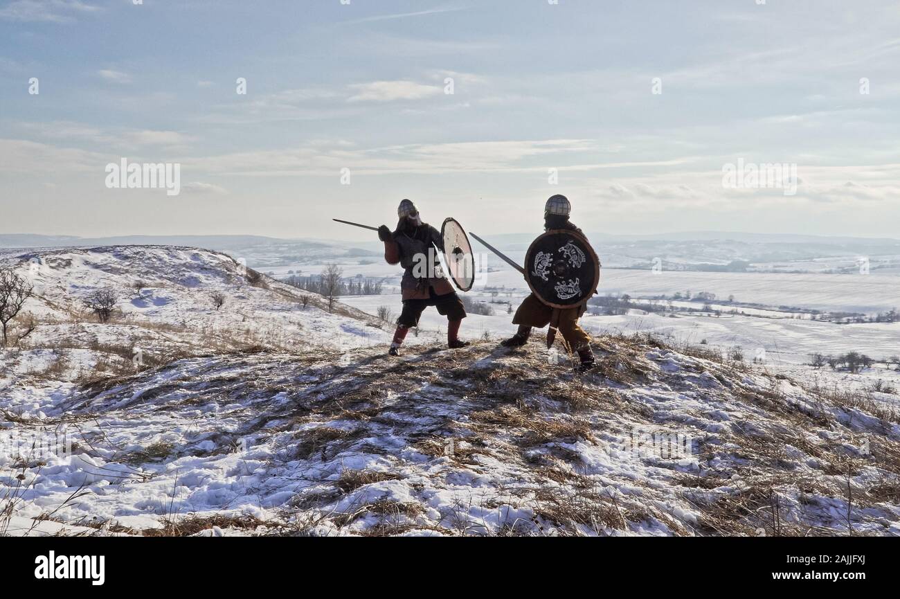 Two viking are fighting with axes and shields on the winter meadow ...