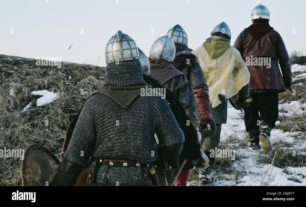 Back view of a group of medieval vikings with arms and shields going on ...