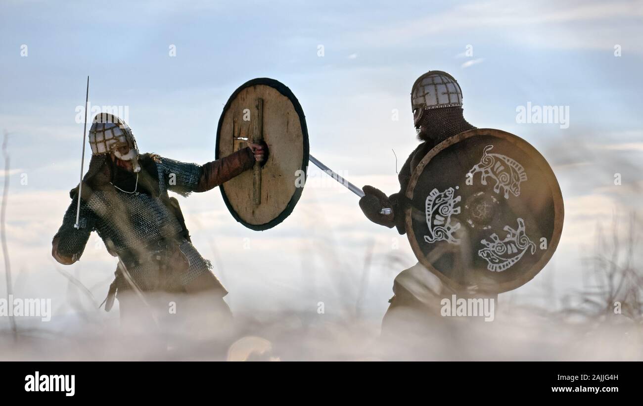 Two warriors viking are fighting with axes and shields on the winter ...