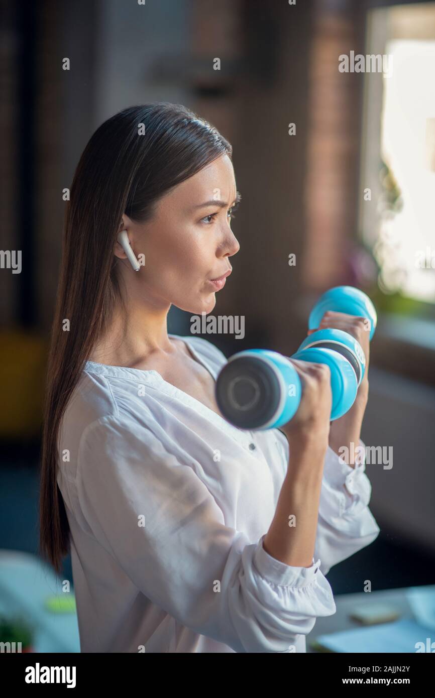 Serious young Asian woman lifting small dumbbells Stock Photo - Alamy