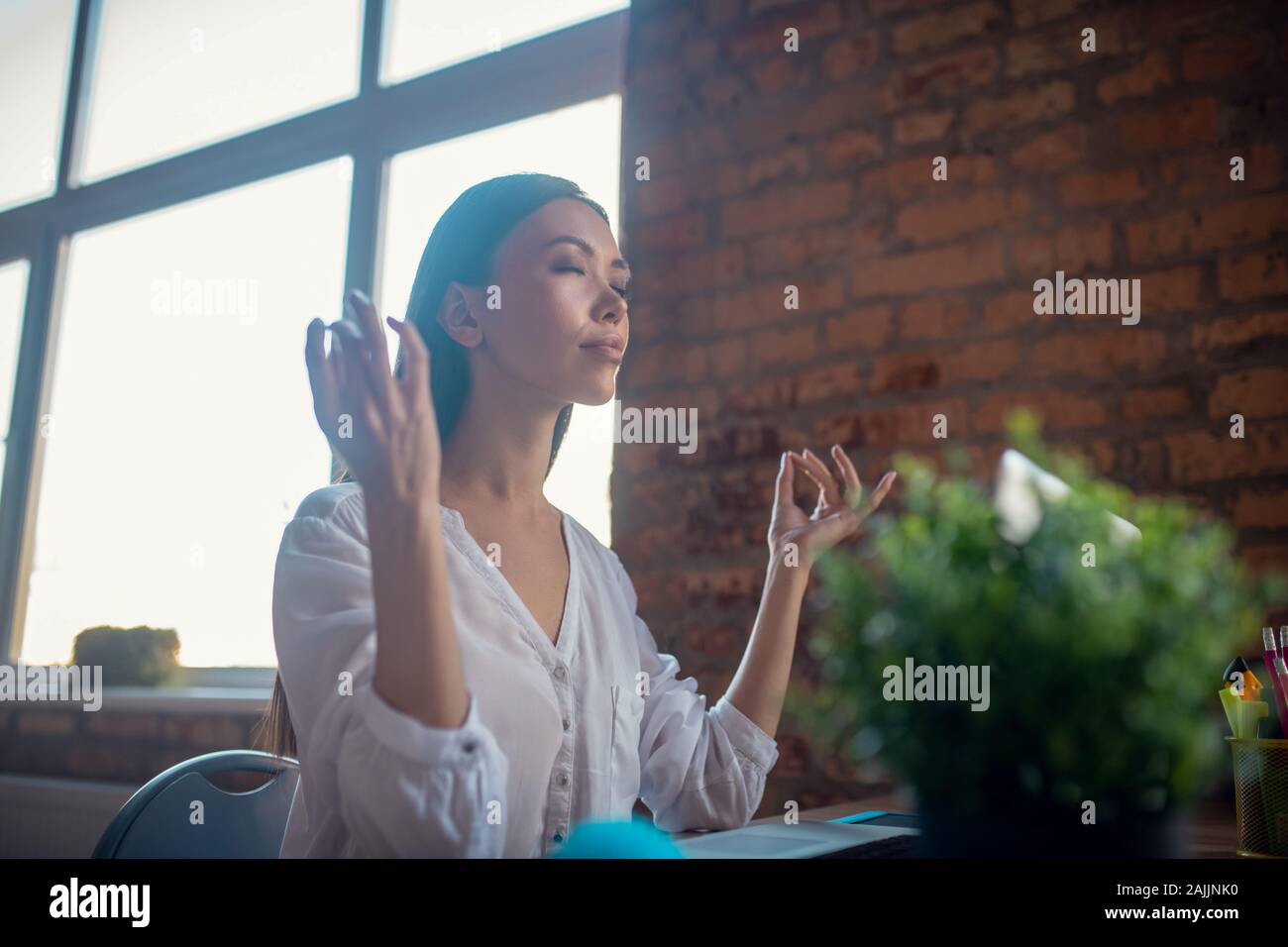 Beautiful calm young woman meditating at work Stock Photo - Alamy