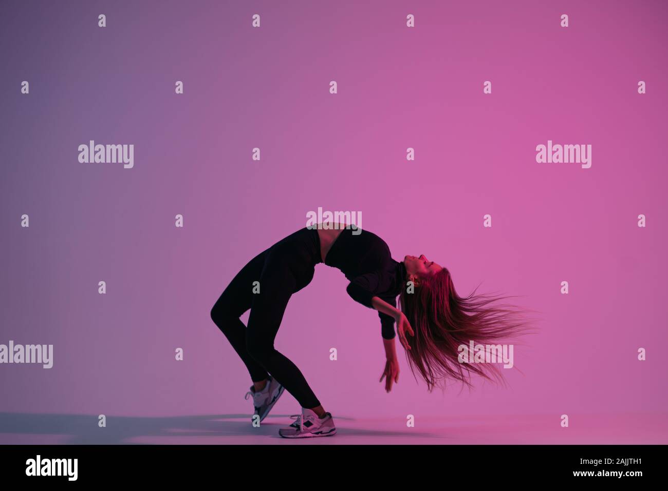 Handsome creative female dancer posing in studio against colorful ...