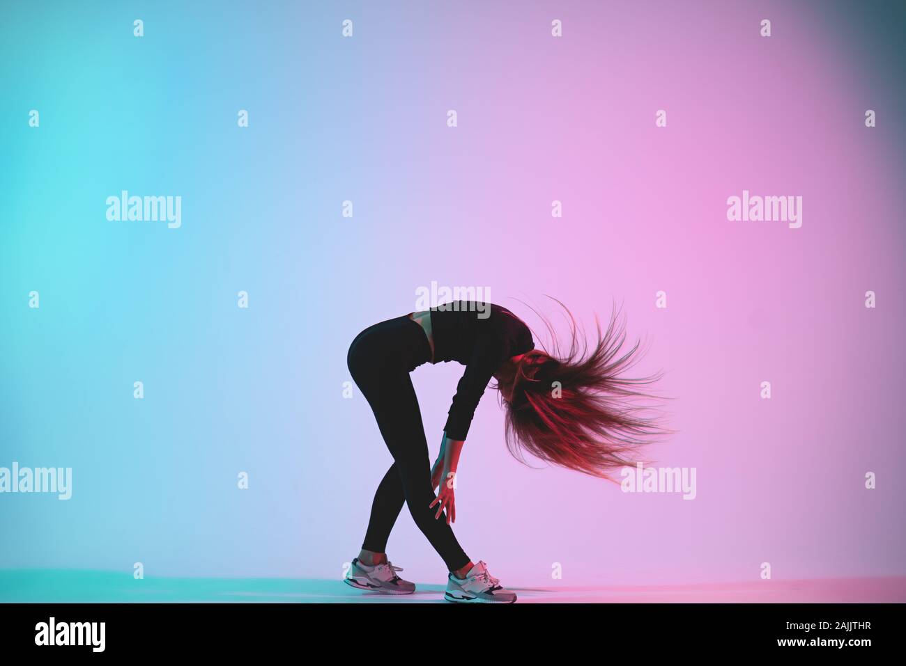 Handsome creative female dancer posing in studio against colorful ...