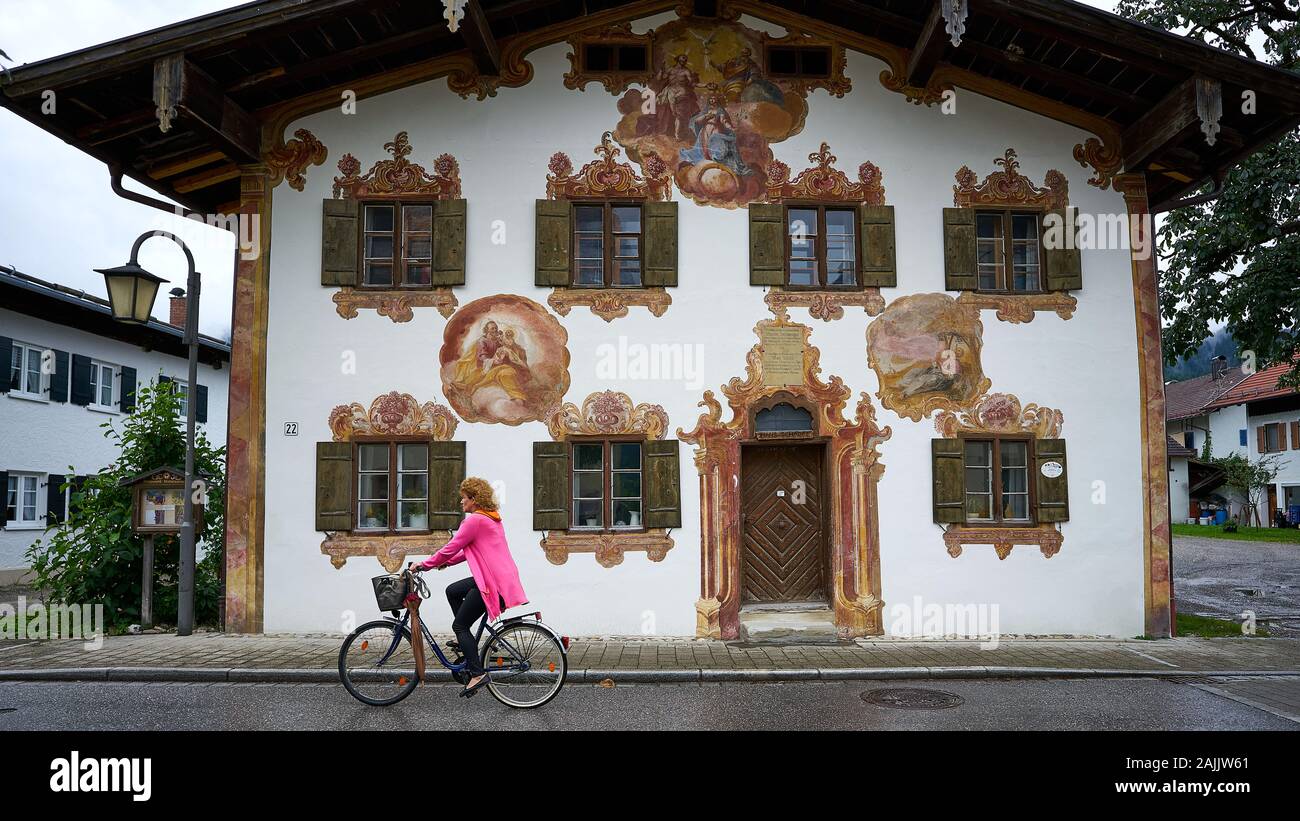 Red headed female cyclist rides past an amazing house facade with ...