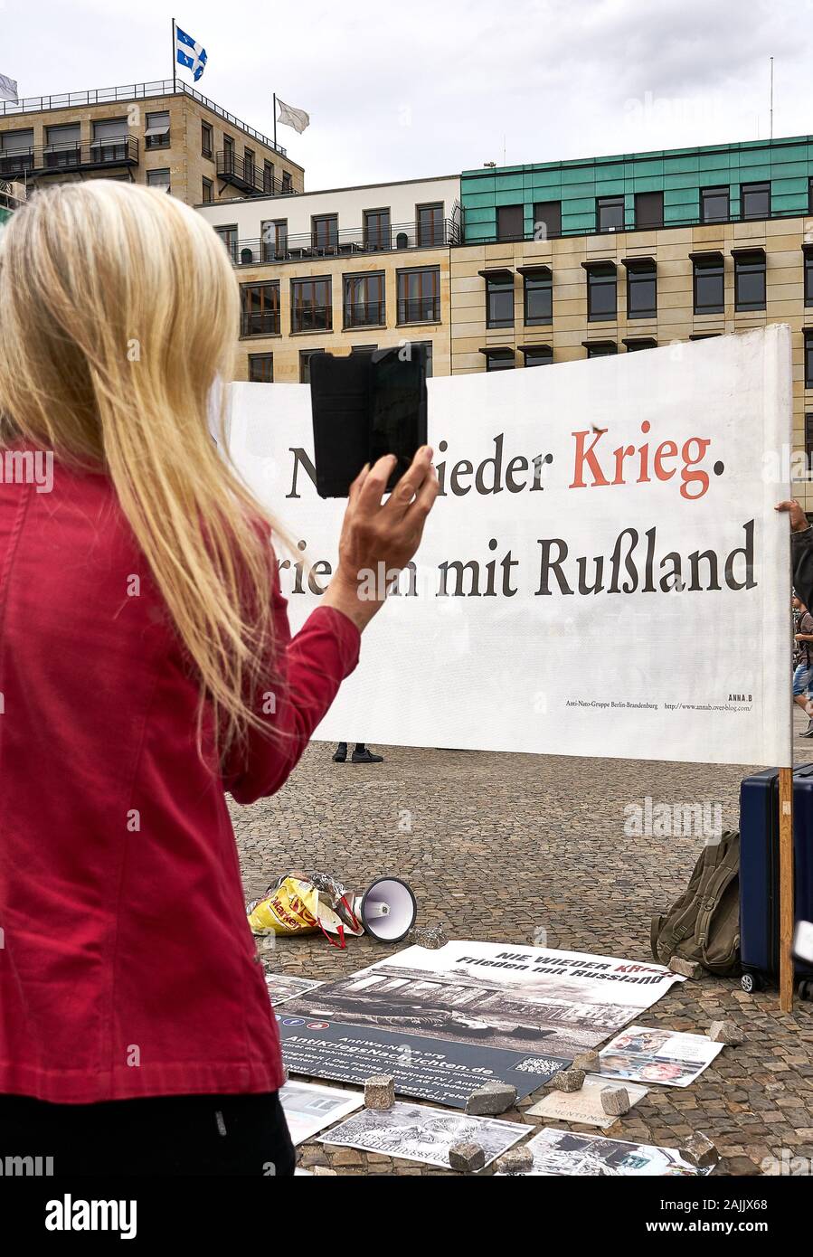 Blonde woman takes cell phone photo of a sign at a peaceful protest in ...