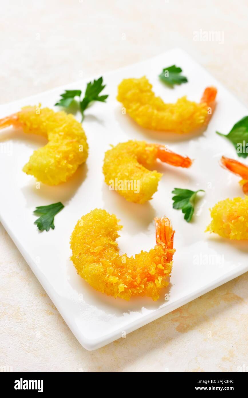 Deep fried breaded prawn on white plate over light stone background ...