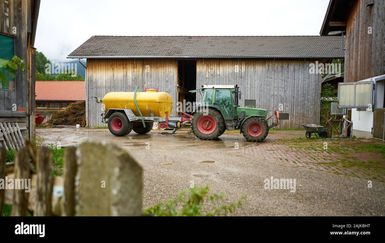 Tractor pulling water tank in a farm enclosure in the Bavarian ...