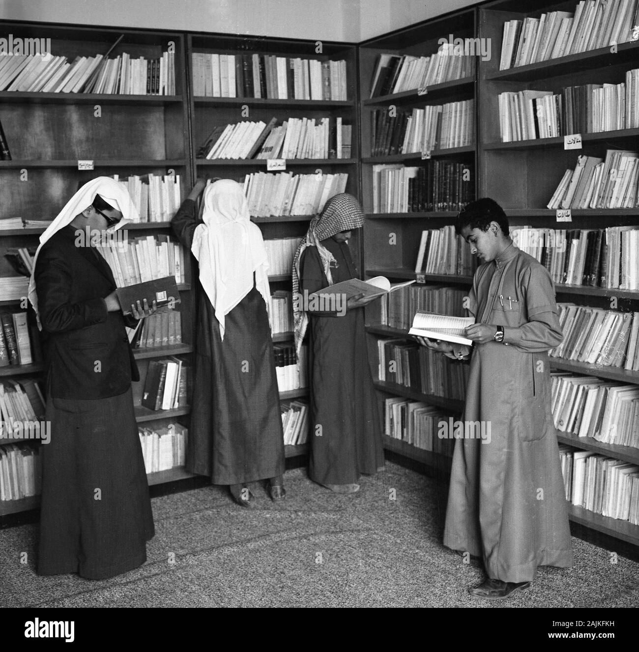1960s, historical, Arab students in traditional dress browsing the ...