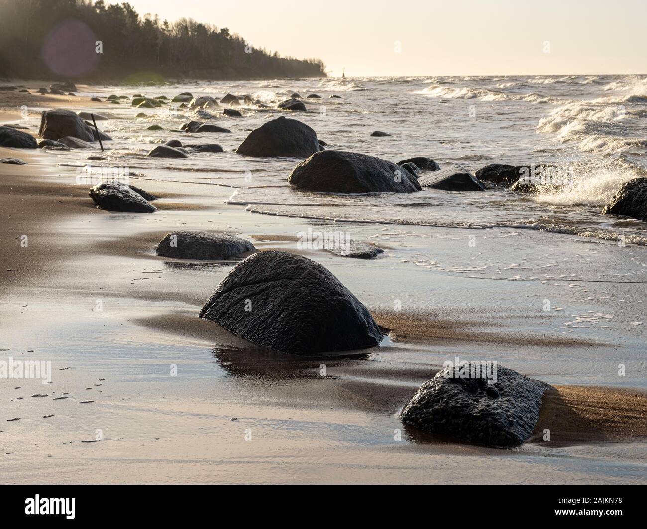 backlit landscape with stony sea shore, dark rocky silhouettes of sea ...