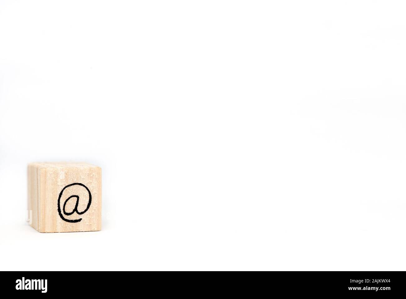 Wooden cube with a commercial At Sign symbol isolated on white ...