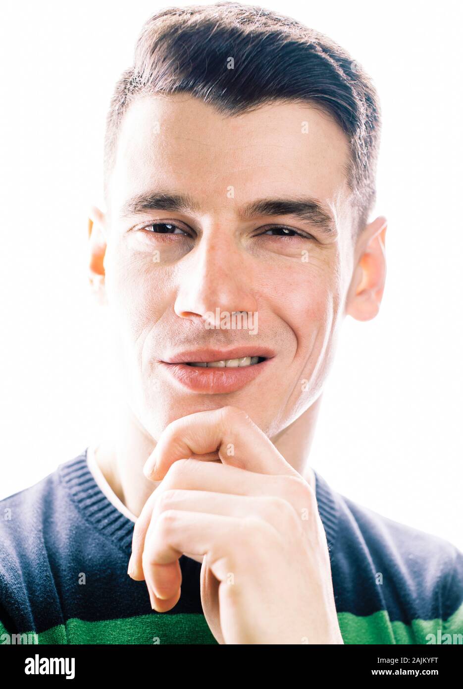 Portrait of a smart serious young man standing against white background ...