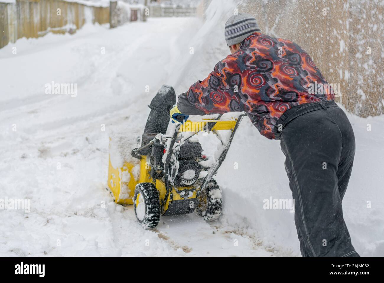 man operating snow blower to remove snow on driveway. Man using a ...