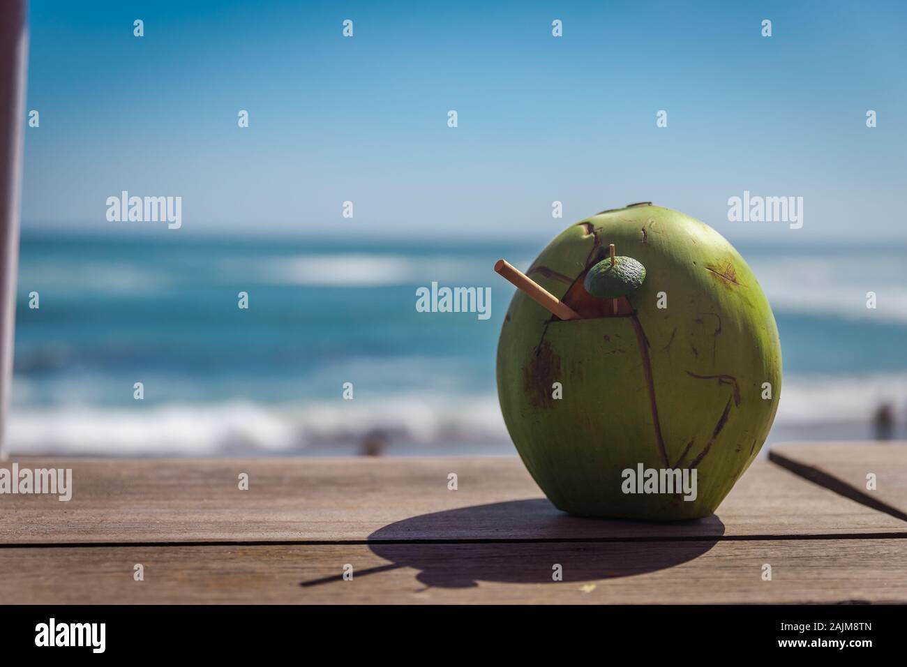 Coconut with a tube on the windowsill. Ocean view. Coconut water drink ...