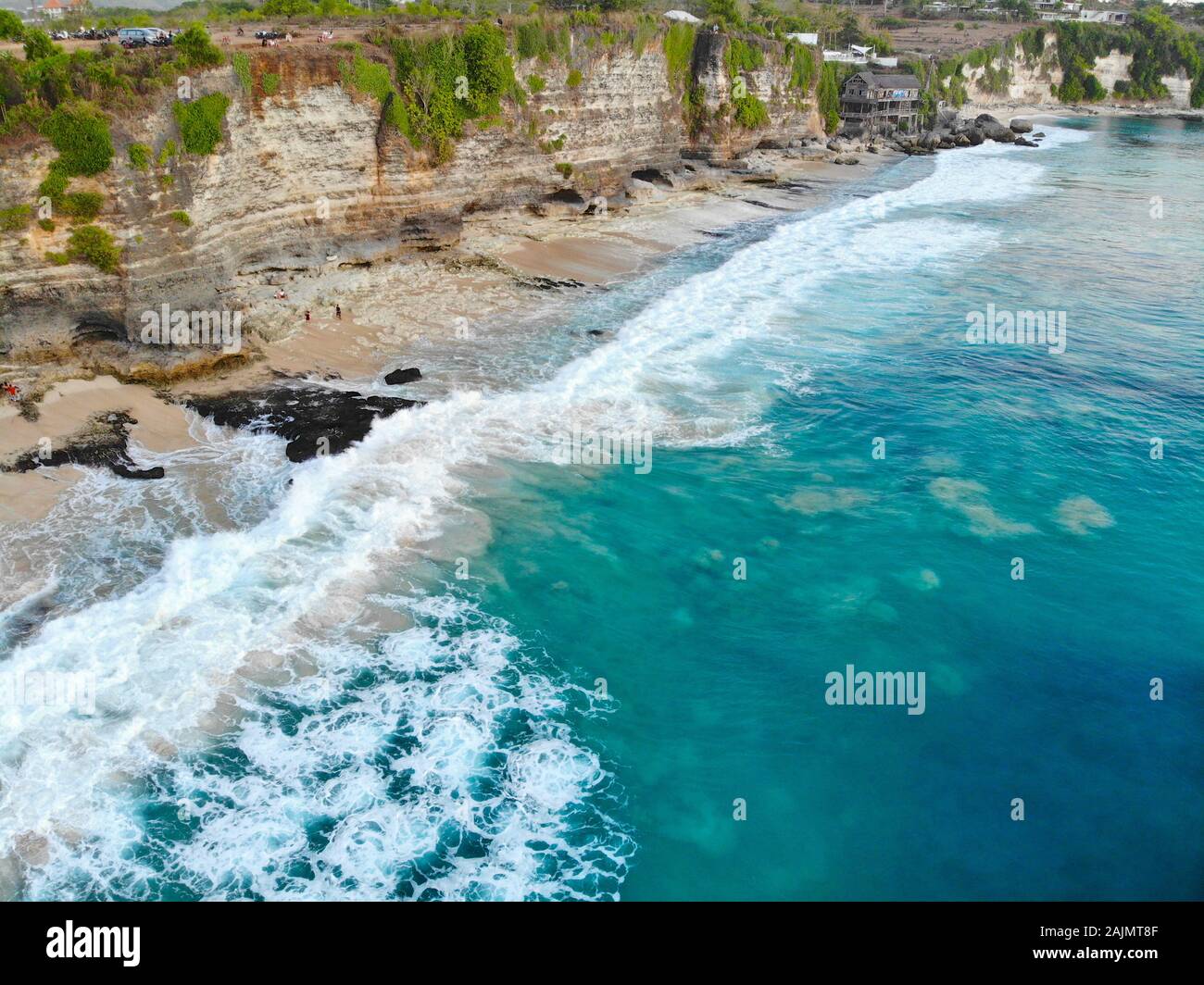 Aerial view of blue clear ocean over sandy coastline with cliff. Waves ...