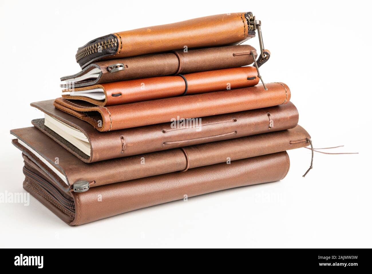 A stack of leather-bound journals, notebooks, cases, and wallets set on ...